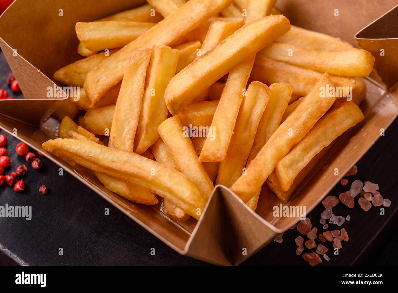 Delicious crispy french fries with salt and spices in a cardboard box ...