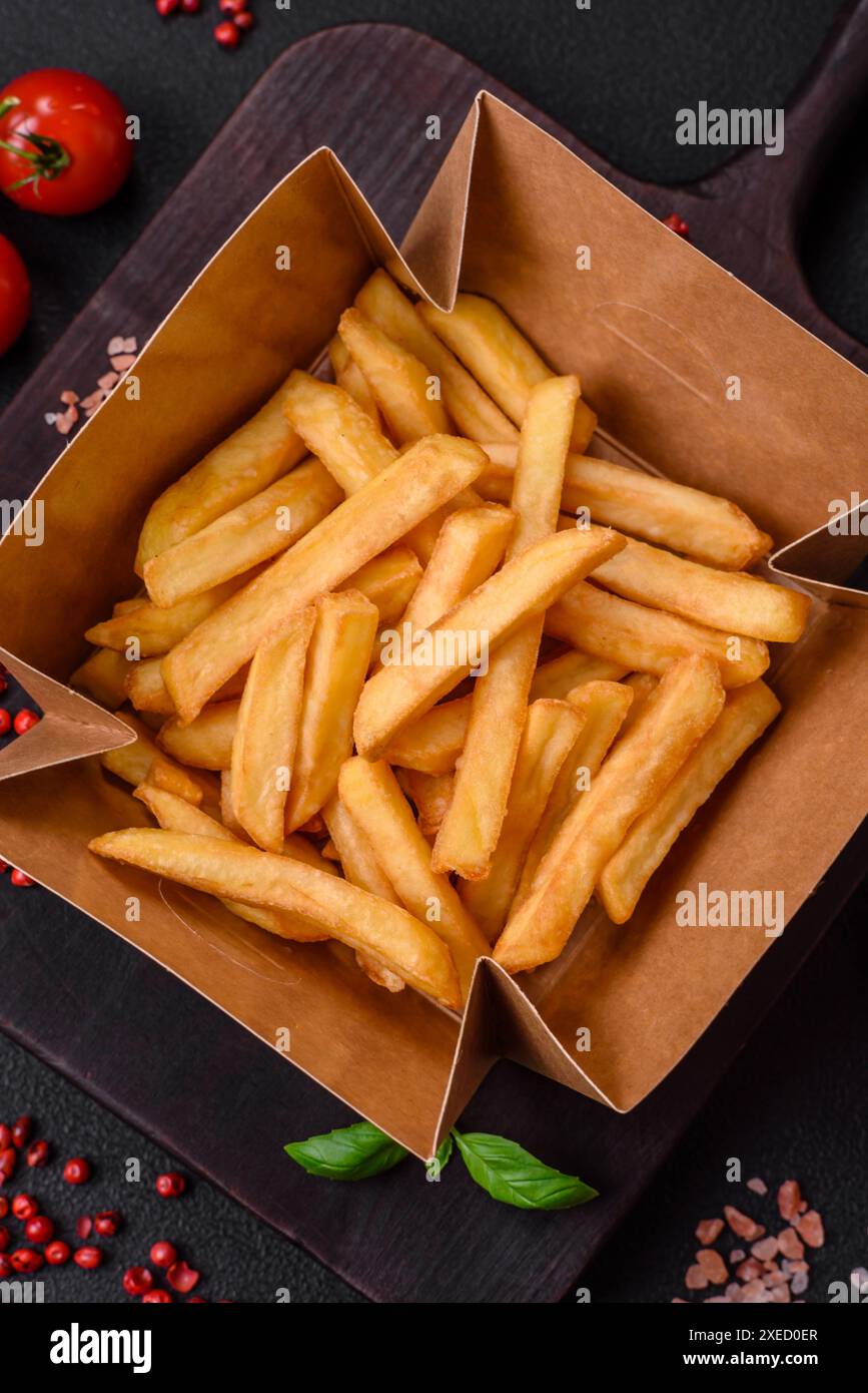 Delicious crispy french fries with salt and spices in a cardboard box ...