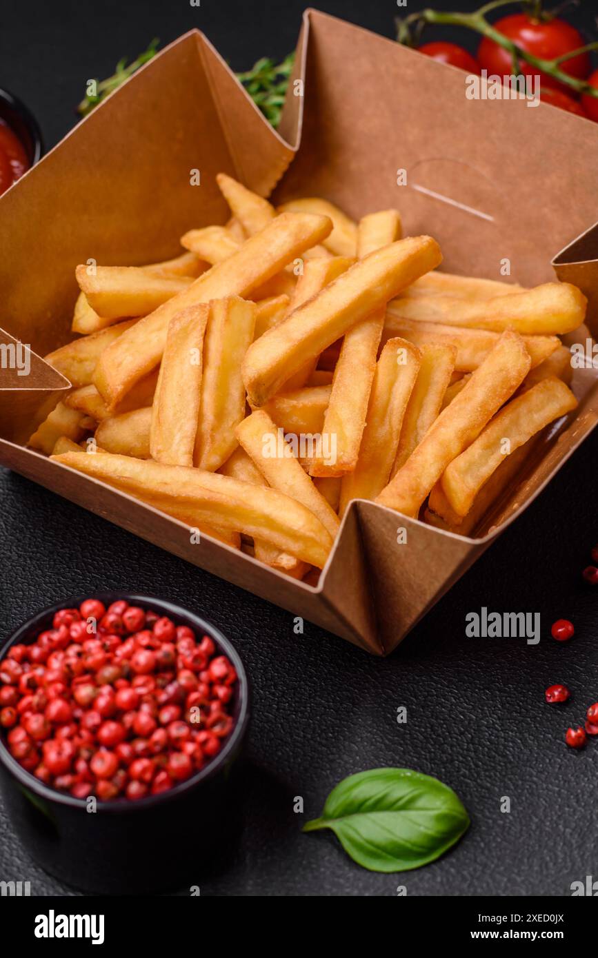 Delicious crispy french fries with salt and spices in a cardboard box ...