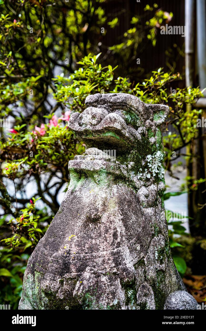 Old statue of a Komainu, a lion-like gatekeeper of Shinto shrine, at ...