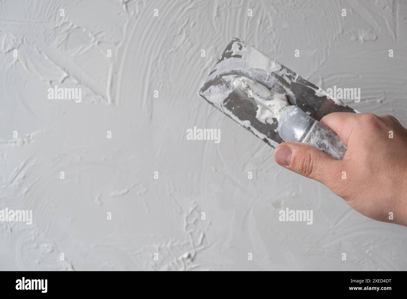 Applying decorative putty. White abstract texture of surface covered ...