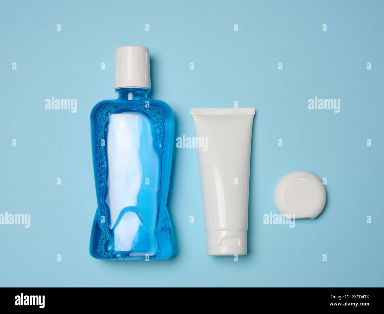 Mouthwash, toothpaste tube, dental floss on a blue background, oral ...