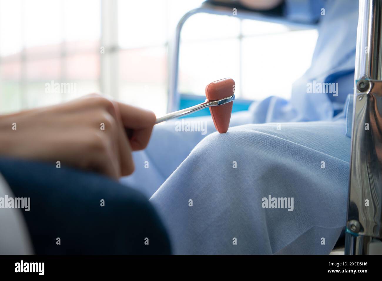 A doctor uses a reflex hammer to evaluate a patient's knee joint Stock ...