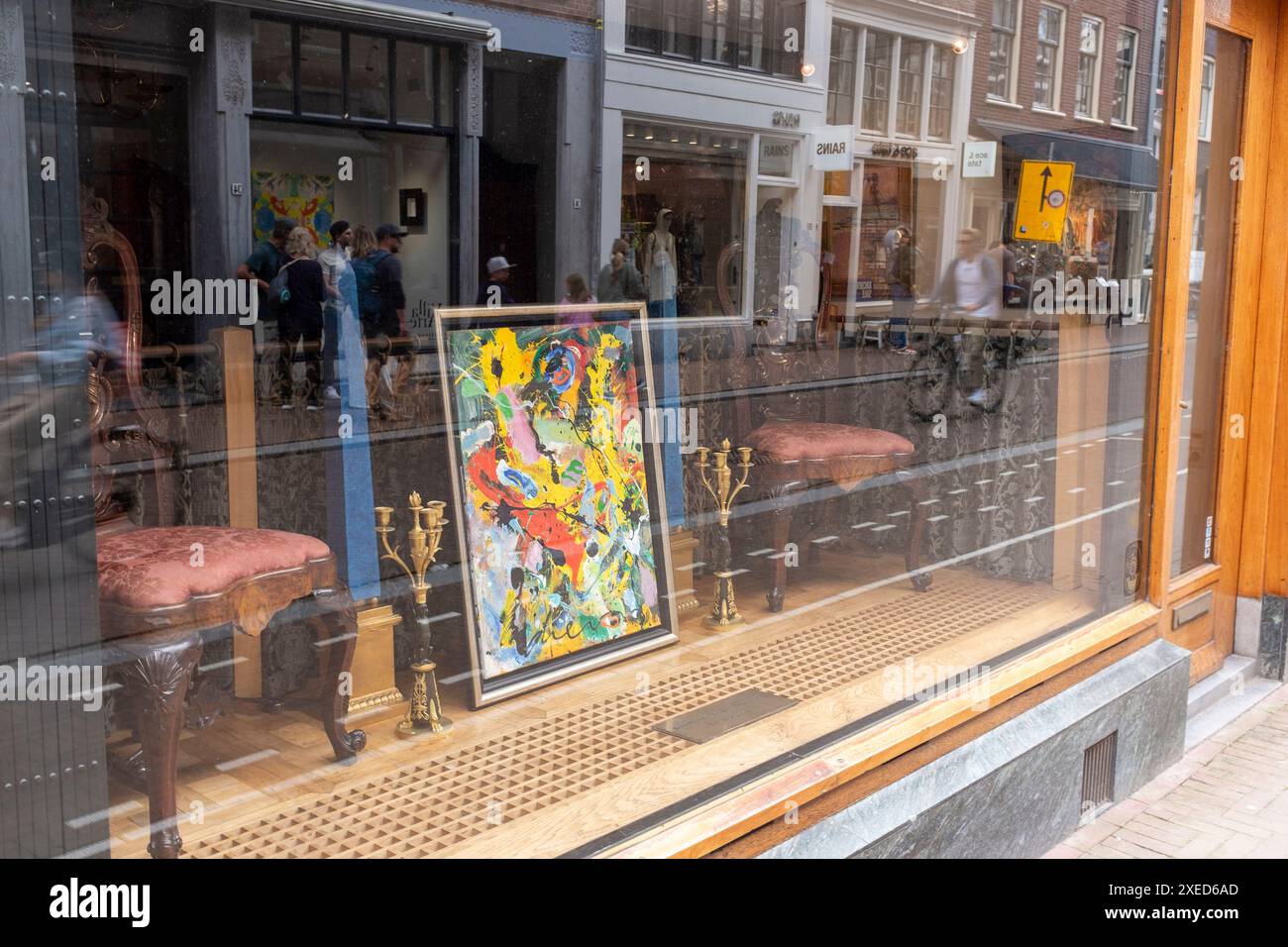Artwork and antiques for sale in shop window, reflecting the street ...