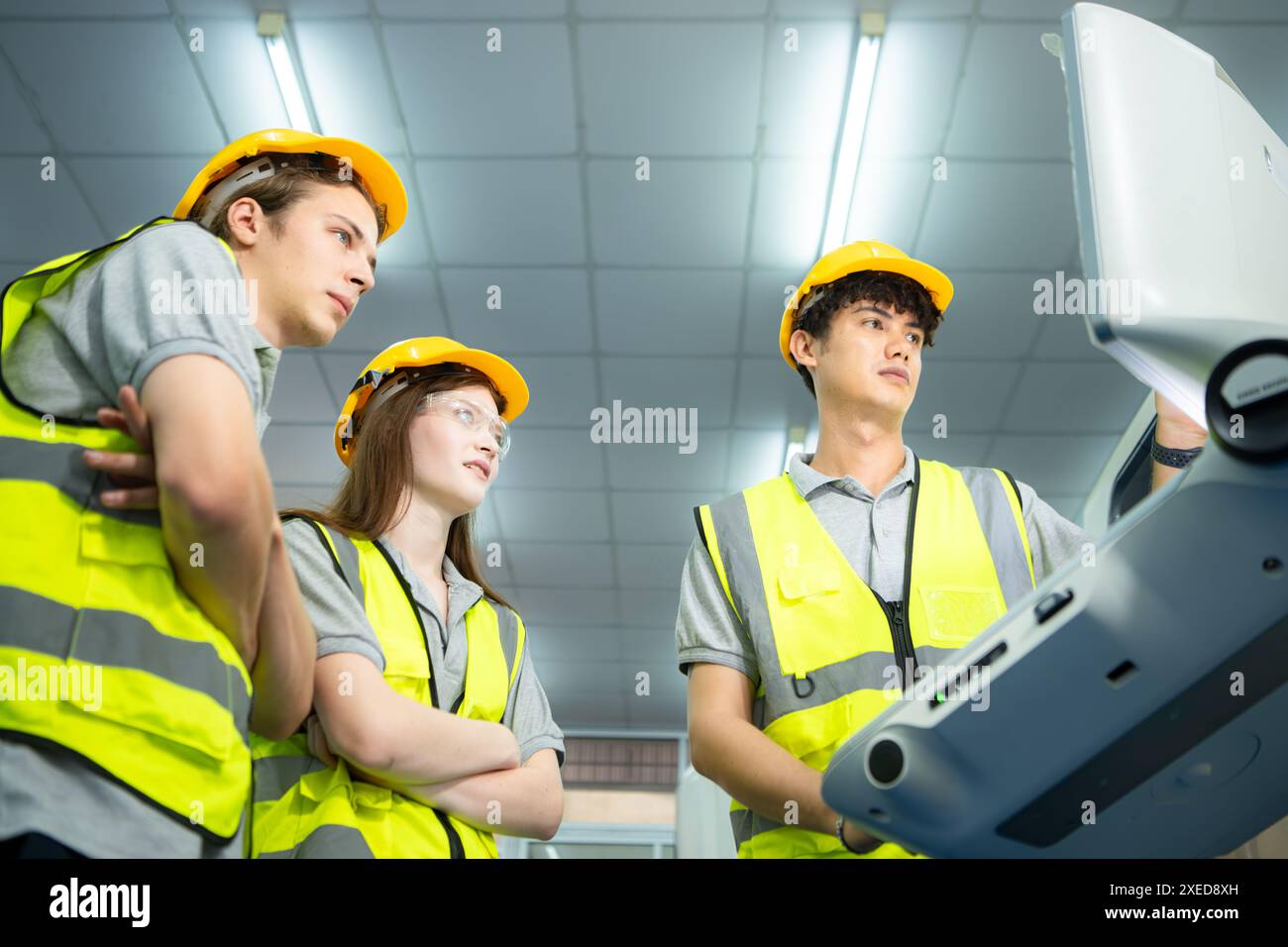Both of young factory worker wearing a hard hat looking at a computer ...