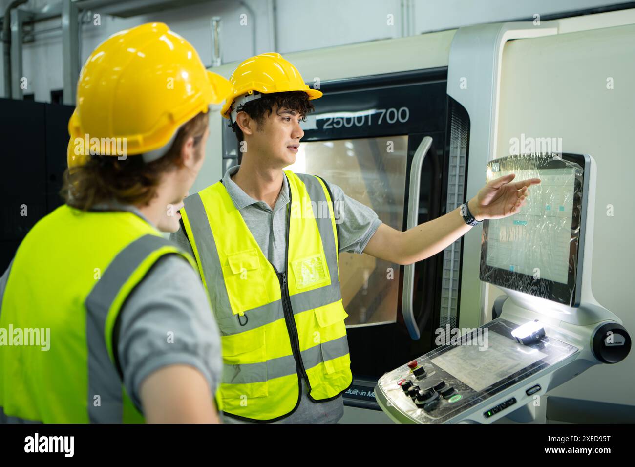 Back view of group young factory worker wearing a hard hat looking at a ...