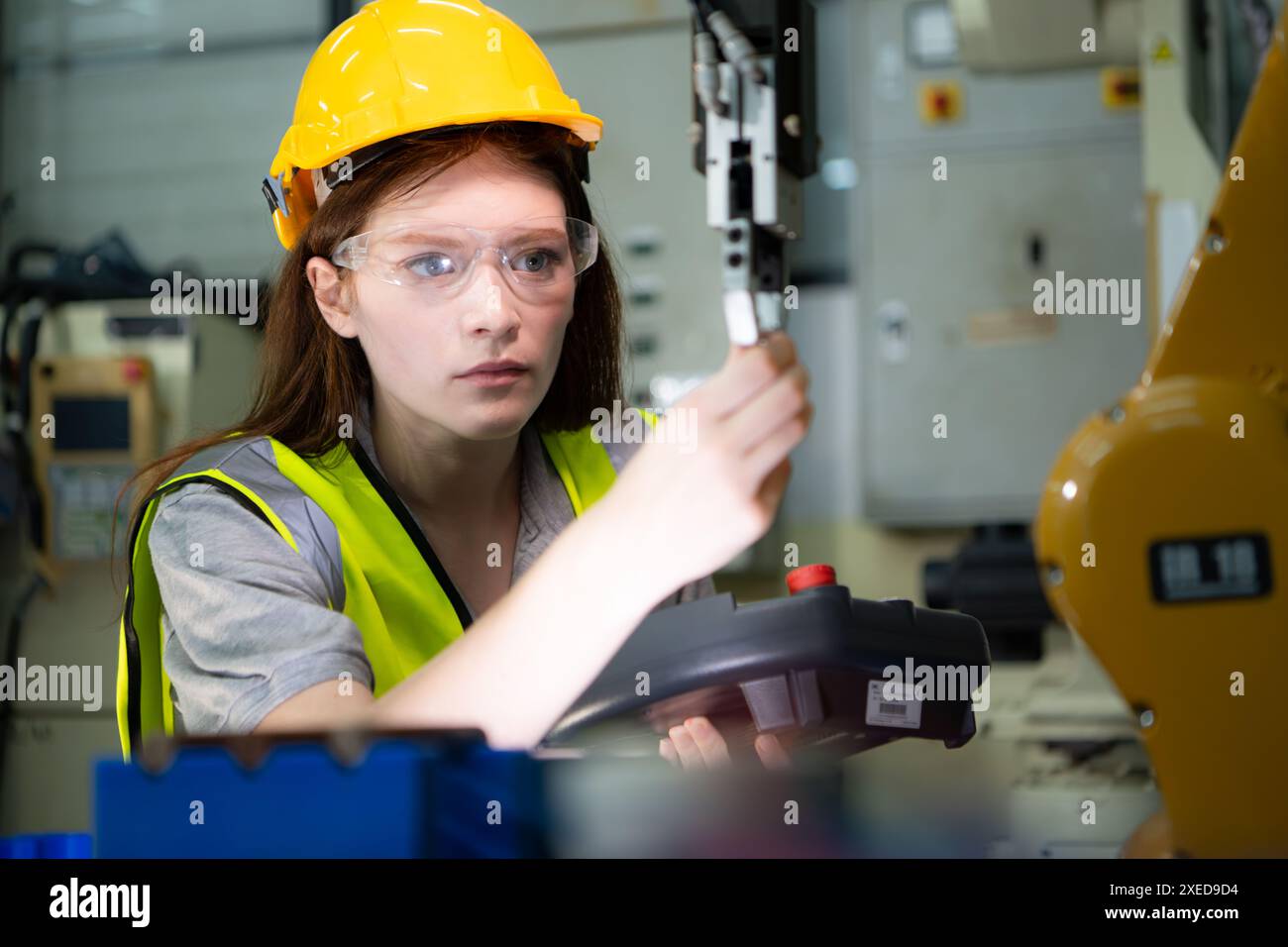 Female technician who maintains a small robot arm the operation of a ...