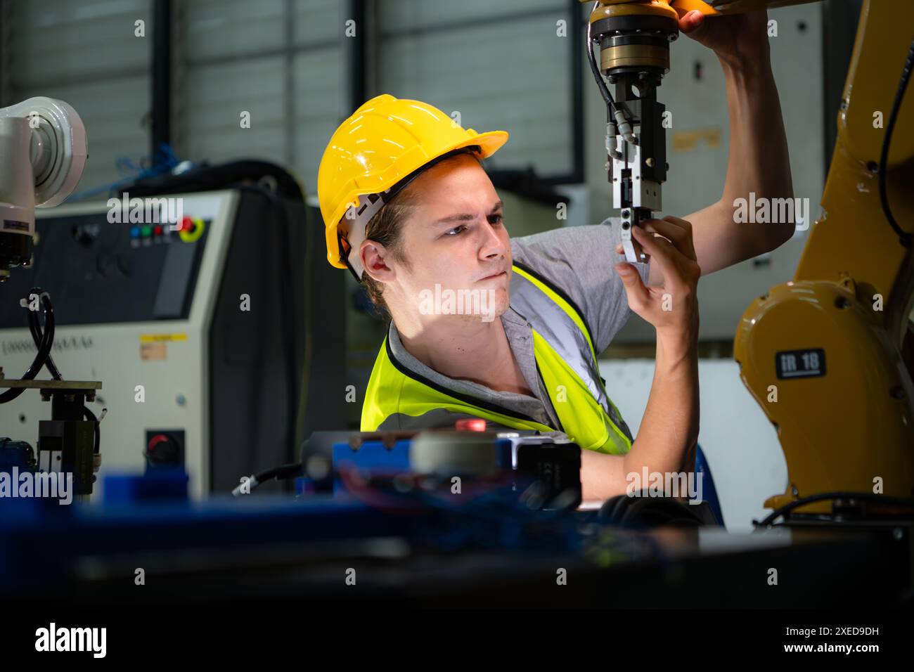 Technician who maintains a small robot arm the operation of a small ...
