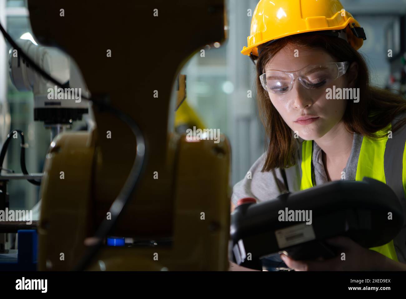 Female technician who maintains a small robot arm the operation of a ...