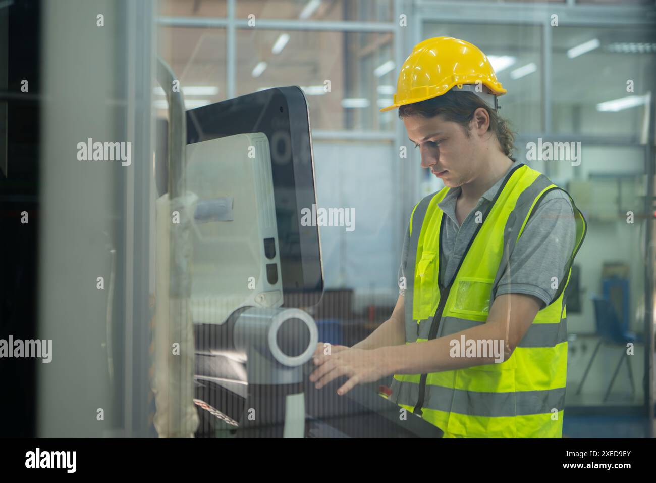 Young man factory worker wearing a hard hat looking at a computer ...