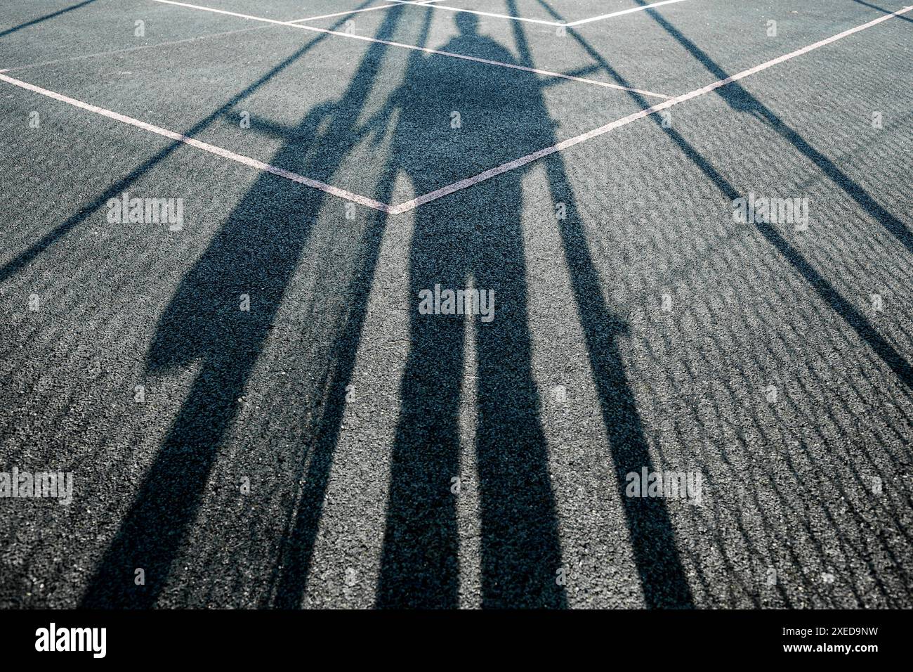A persons figure casting a shadow over an artificial sports pitch ...