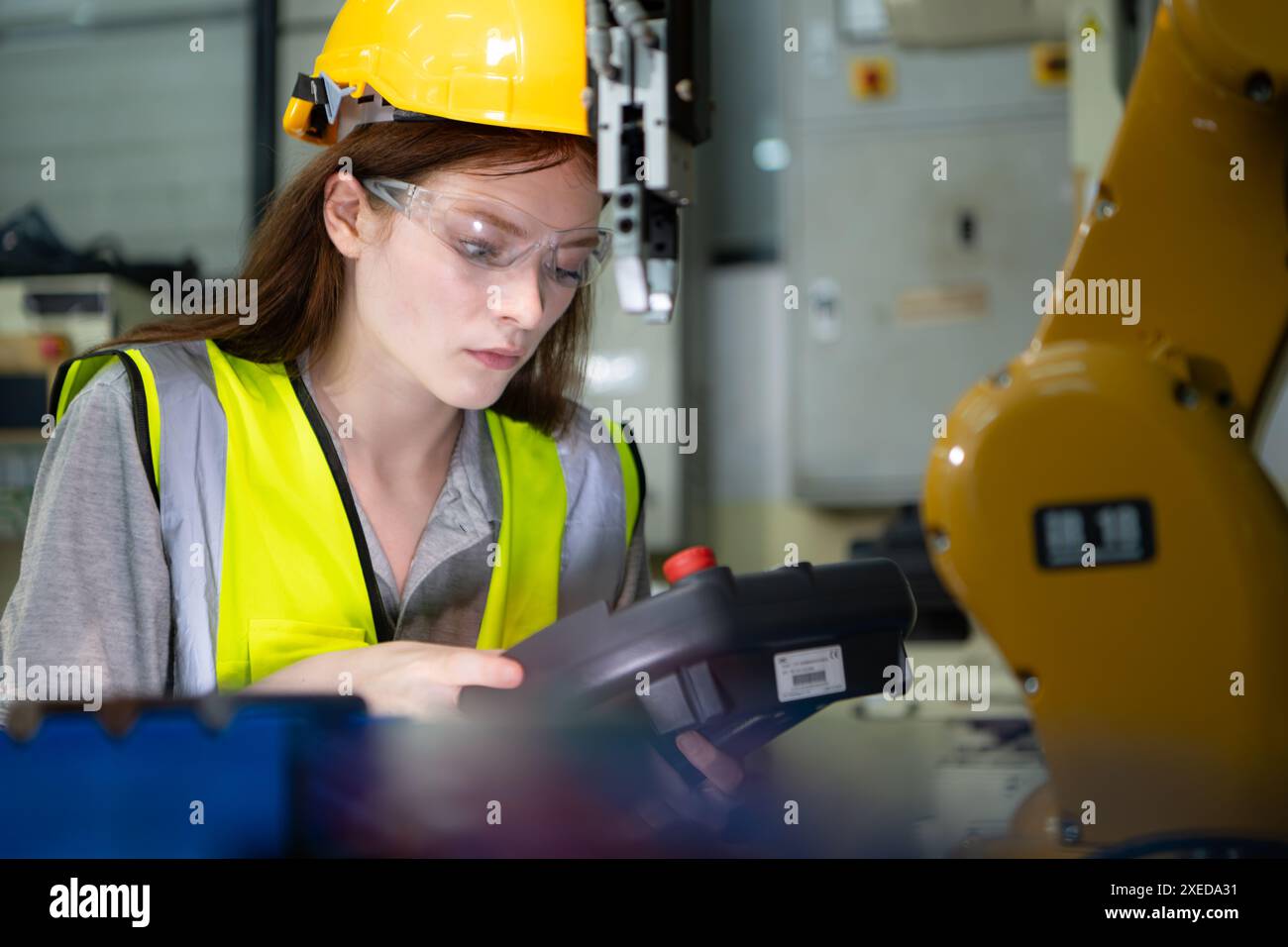 Female technician who maintains a small robot arm the operation of a ...