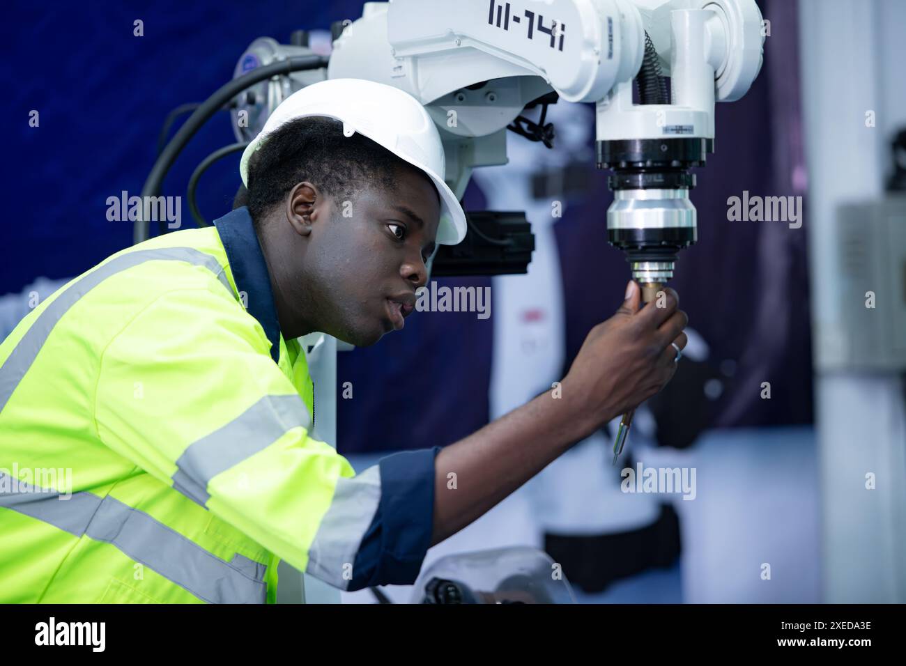 Technician who maintains a small robot arm the operation of a small ...