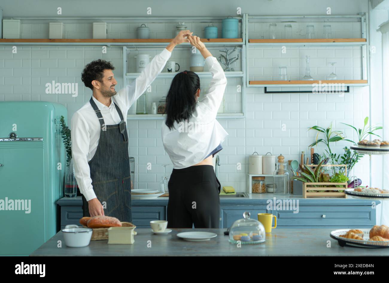 A husband wears an apron while cooking dinner with his wife. He was ...