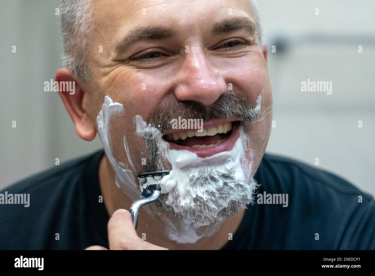 Middle aged handsome man shaving his beard in bathroom Stock Photo - Alamy