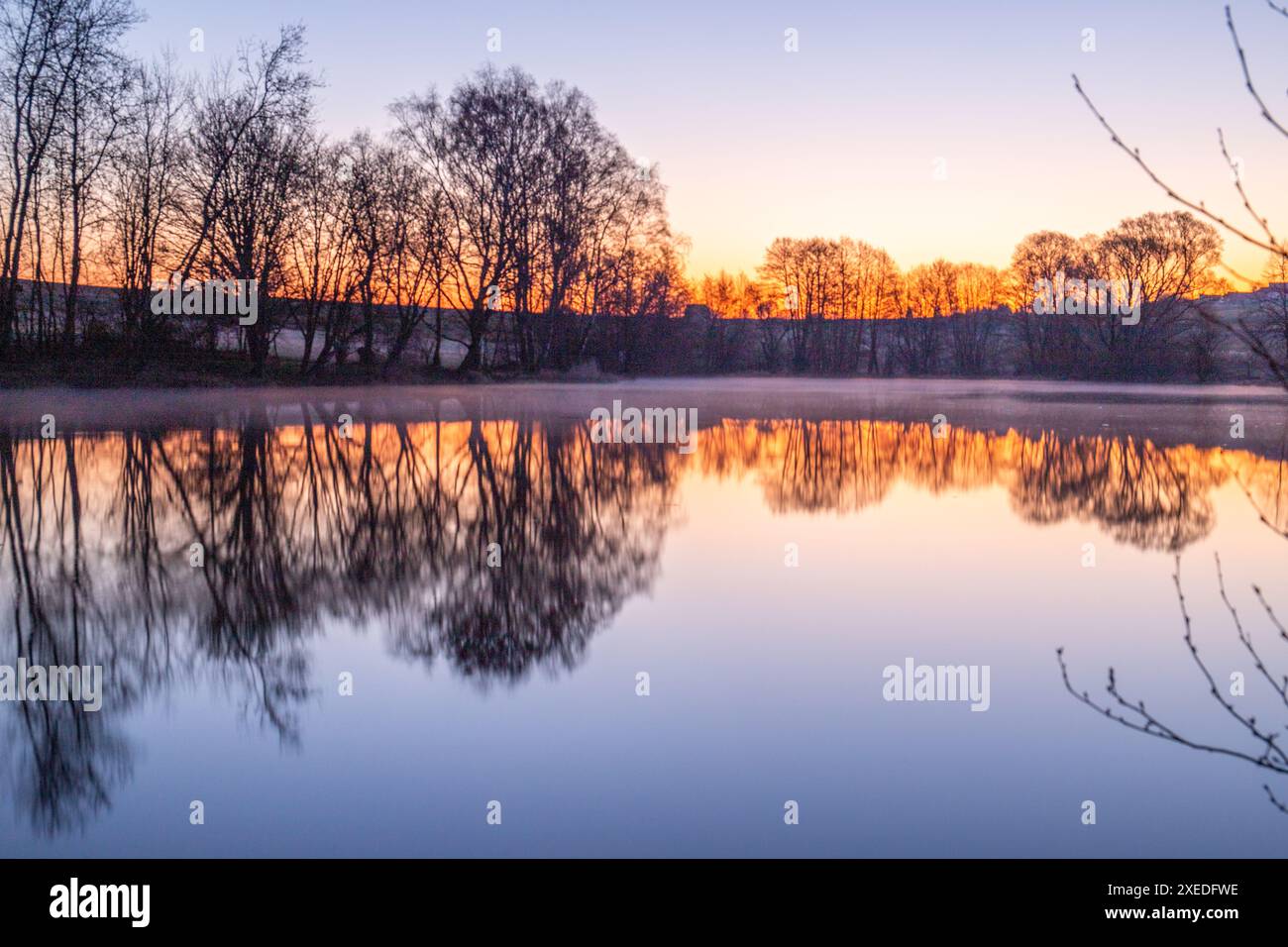 Sunset on a quiet lake in a valley surrounded by a forest Dutenhofener ...
