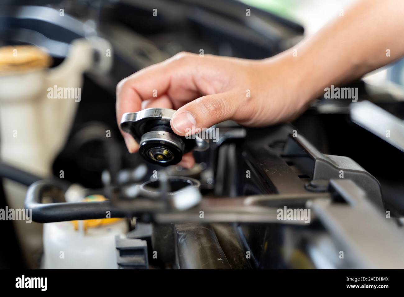 A person is holding a funnel and pouring coolant into the radiator of a ...