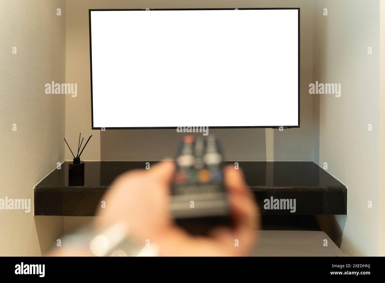 A person is relaxing on a sofa while holding a remote control in front ...