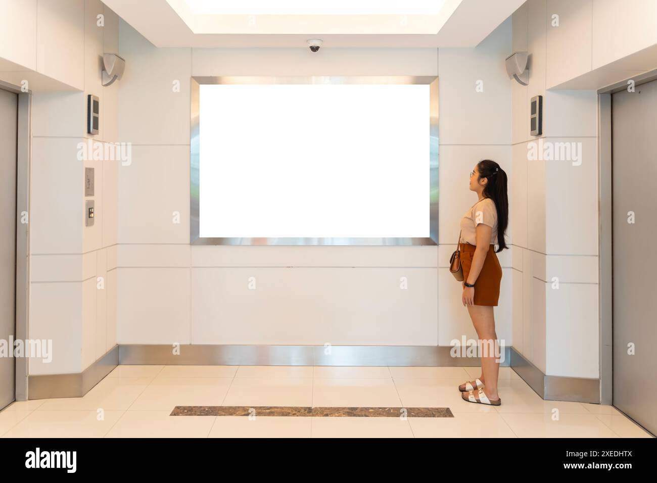 A woman reads an advertisement for a new product on an elevator screen ...