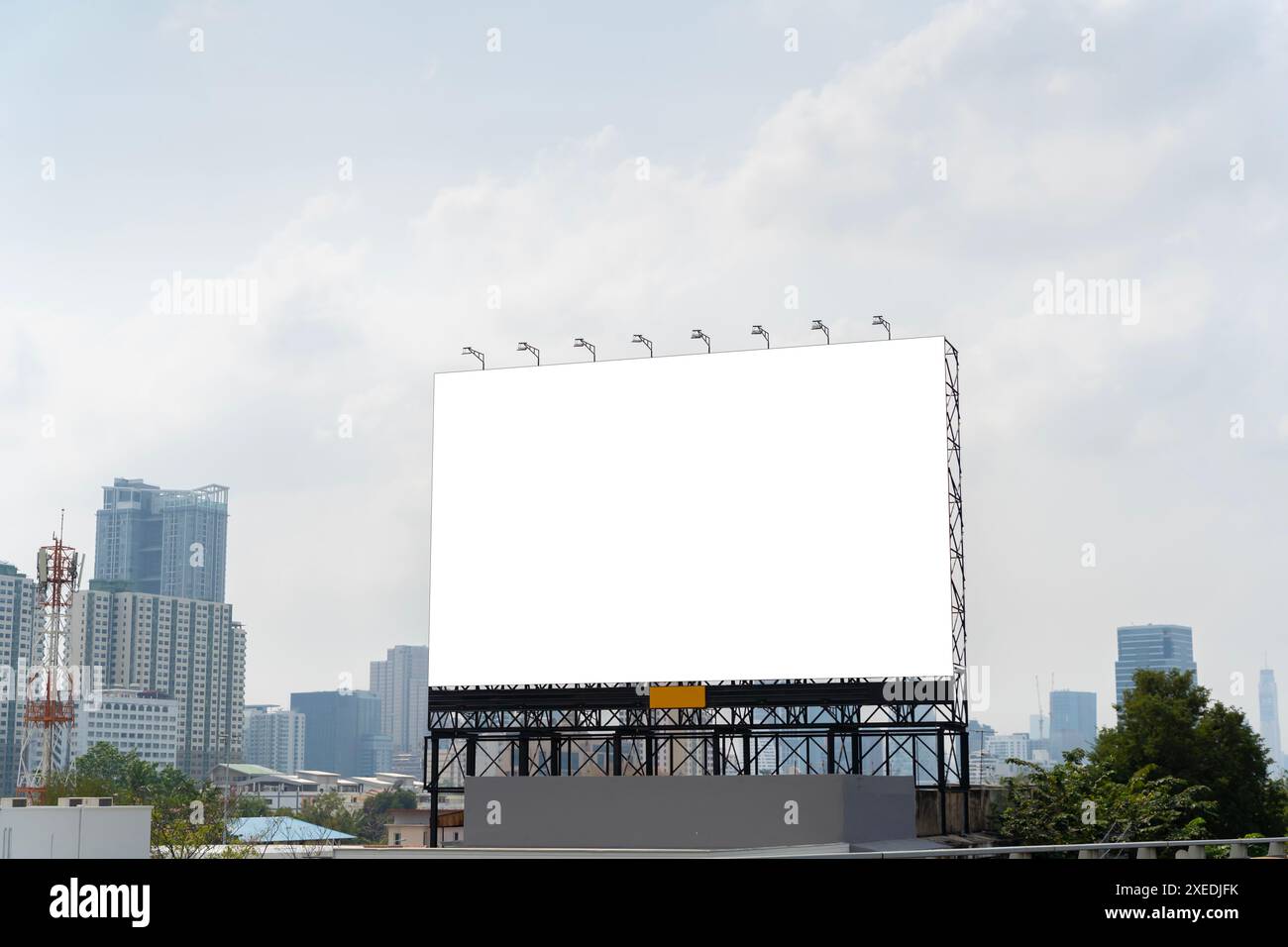 The image shows a large blank billboard in the middle of a cityscape ...