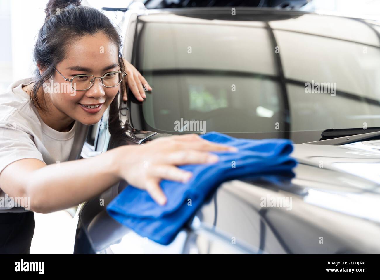 Woman wiping a car with a cloth and is using the cloth to remove dirt ...