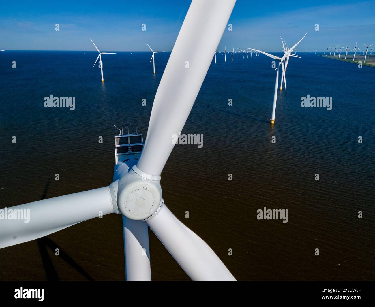 Windmill turbines energy from the wind in the middle of a vast body of ...