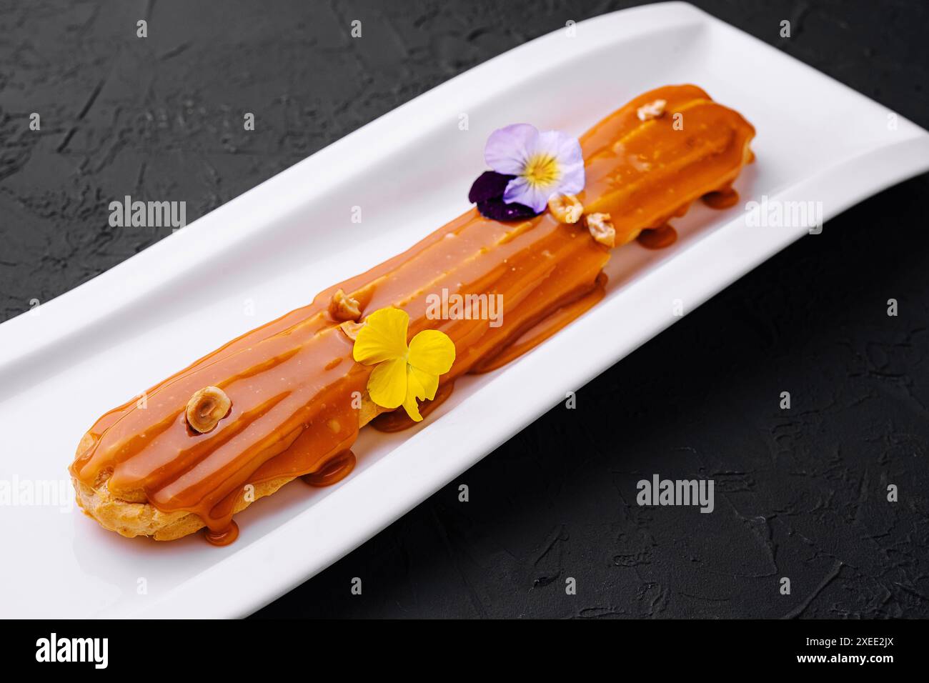 caramel French eclair pastry on white rectangle plate Stock Photo - Alamy