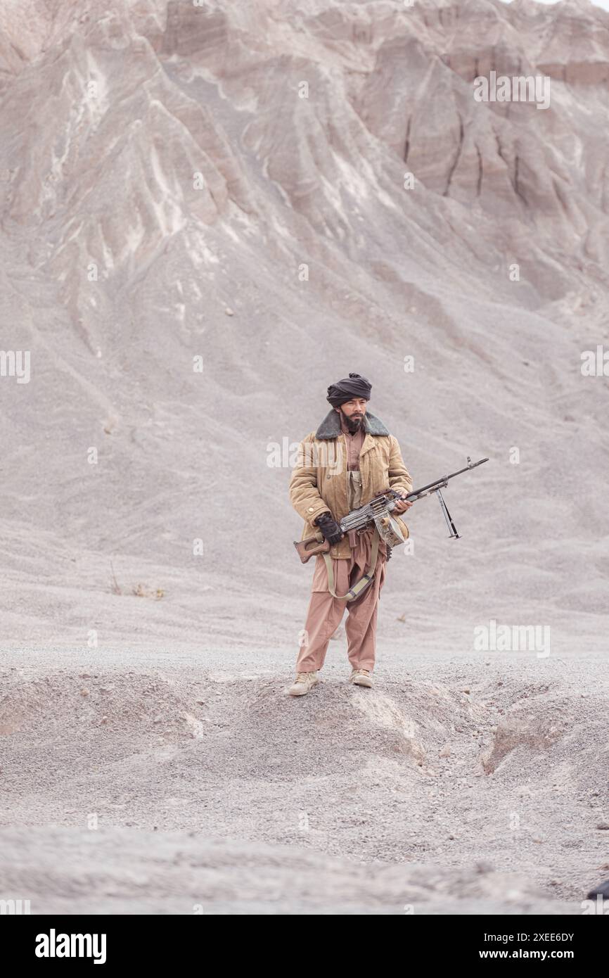 A Taliban soldier stands with a machine gun, In the desert mountain ...