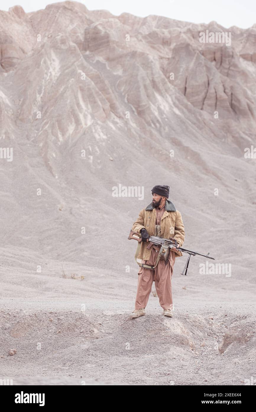 A Taliban soldier stands with a machine gun, In the desert mountain ...