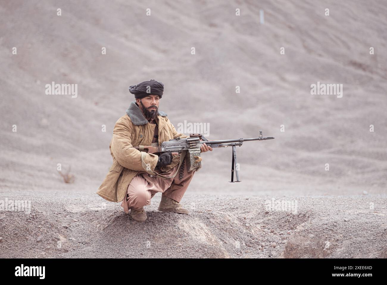 A Taliban soldier with a machine gun, In the desert mountain landscape ...