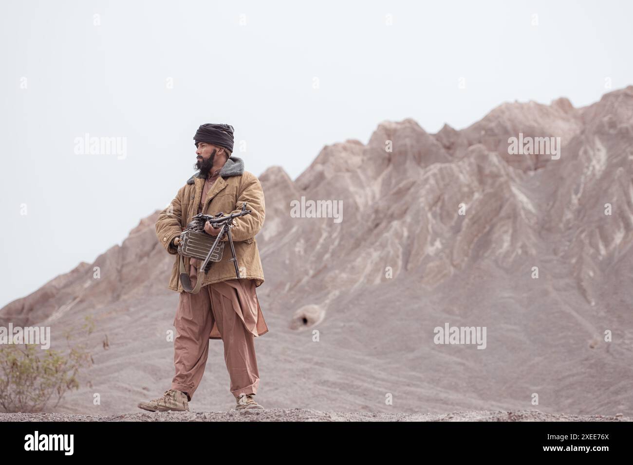 A Taliban soldier stands with a machine gun, In the desert mountain ...