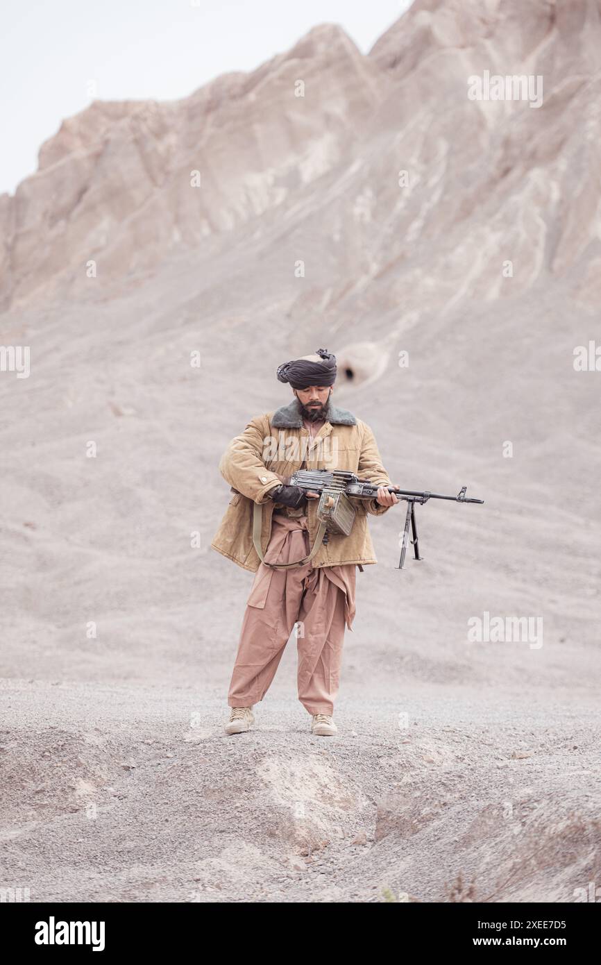 A Taliban soldier stands with a machine gun, In the desert mountain ...