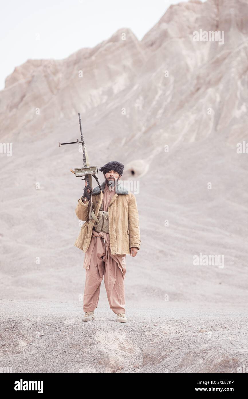 A Taliban soldier stands with a machine gun, In the desert mountain ...