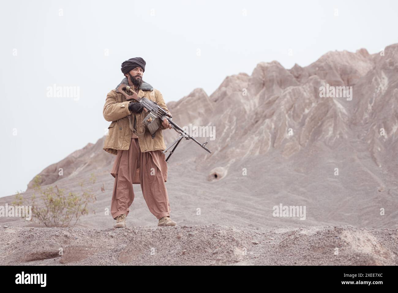 A Taliban soldier stands with a machine gun, In the desert mountain ...