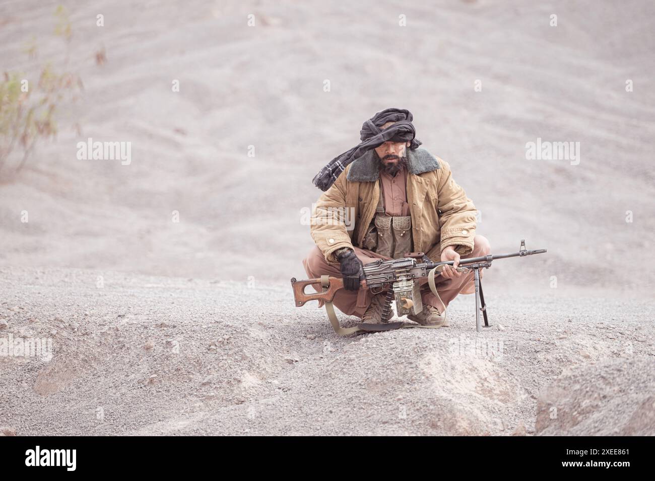 A Taliban soldier with a machine gun, In the desert mountain landscape ...