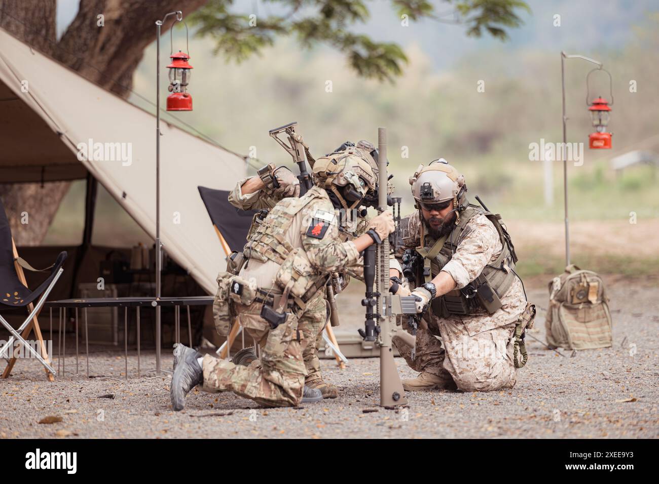 Group of soldiers in camouflage uniforms hold weapons in front of camp ...