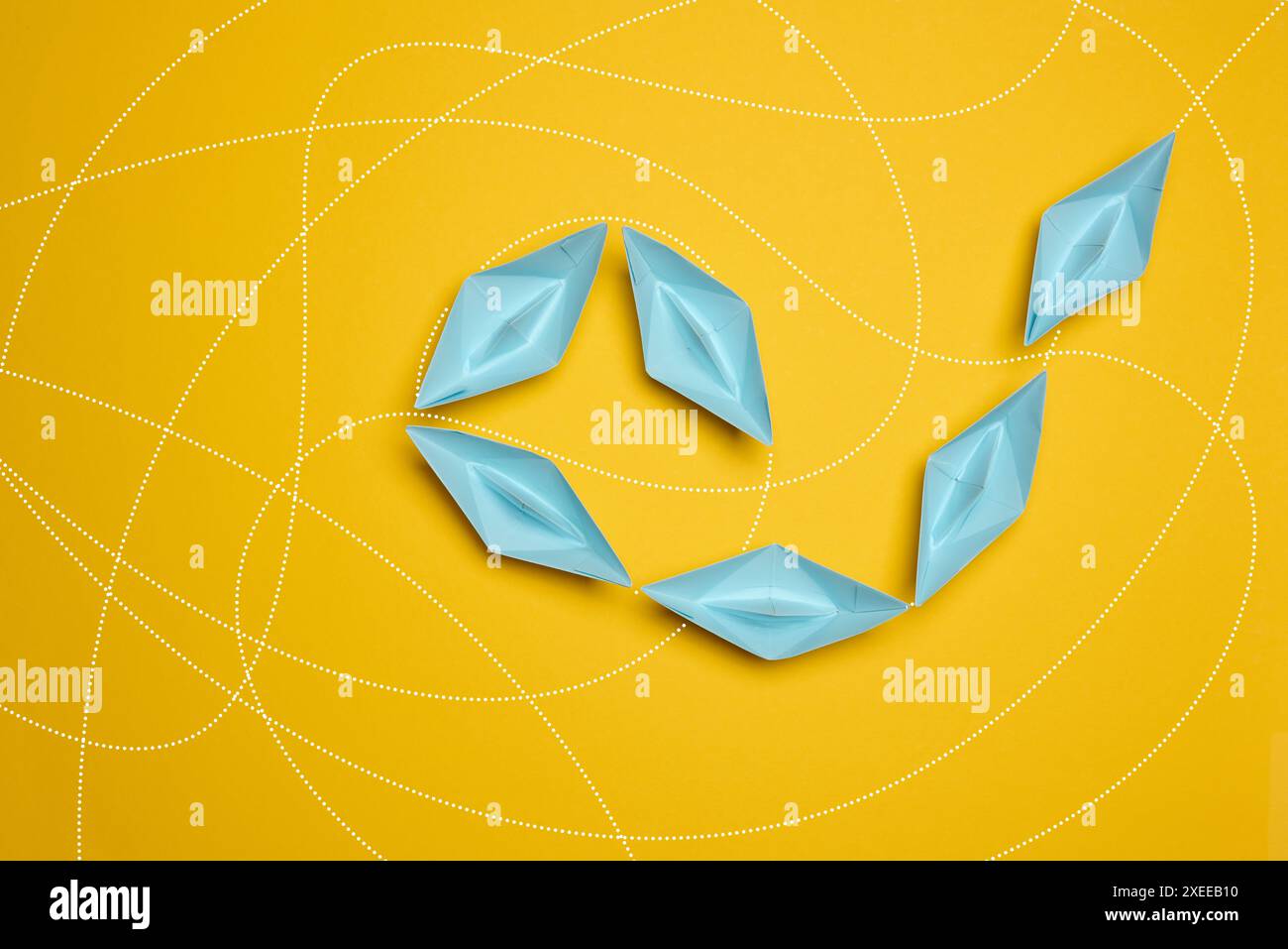 Blue paper boats move one after another on a yellow background, top ...