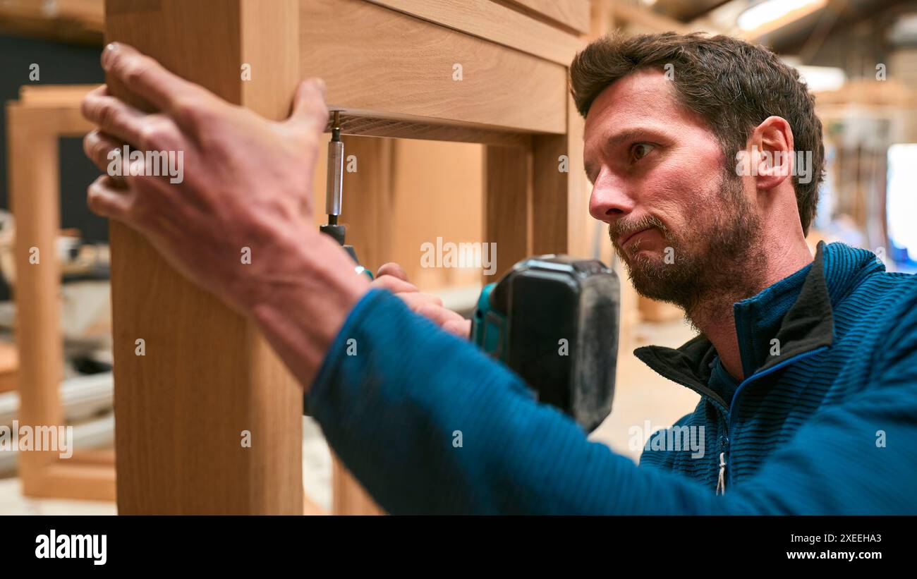 Carpenter In Workshop Using Drill To Attach Piece Of Wood To Window ...