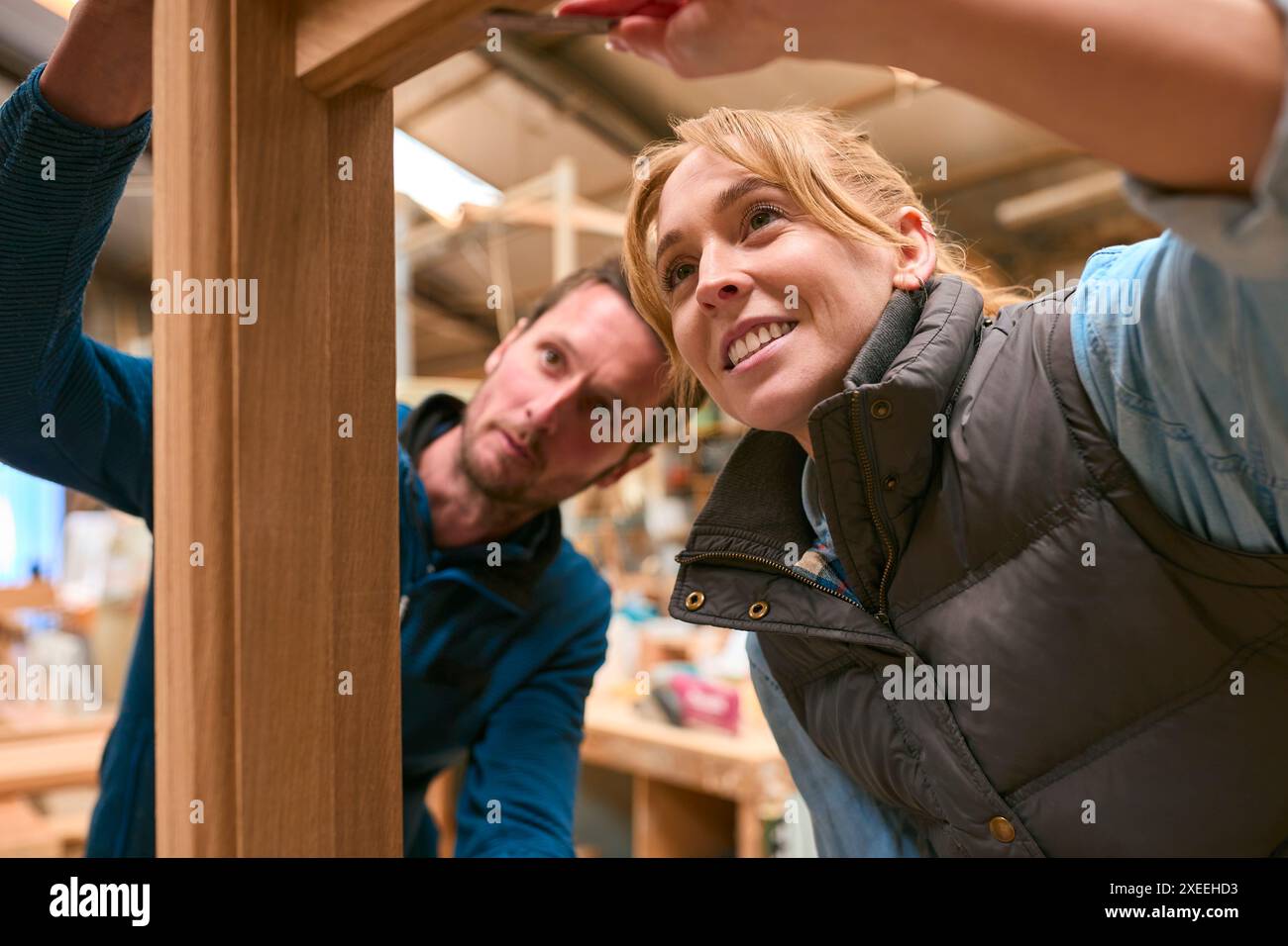 Carpenter With Female Apprentice In Workshop Using Ruler To Measure ...