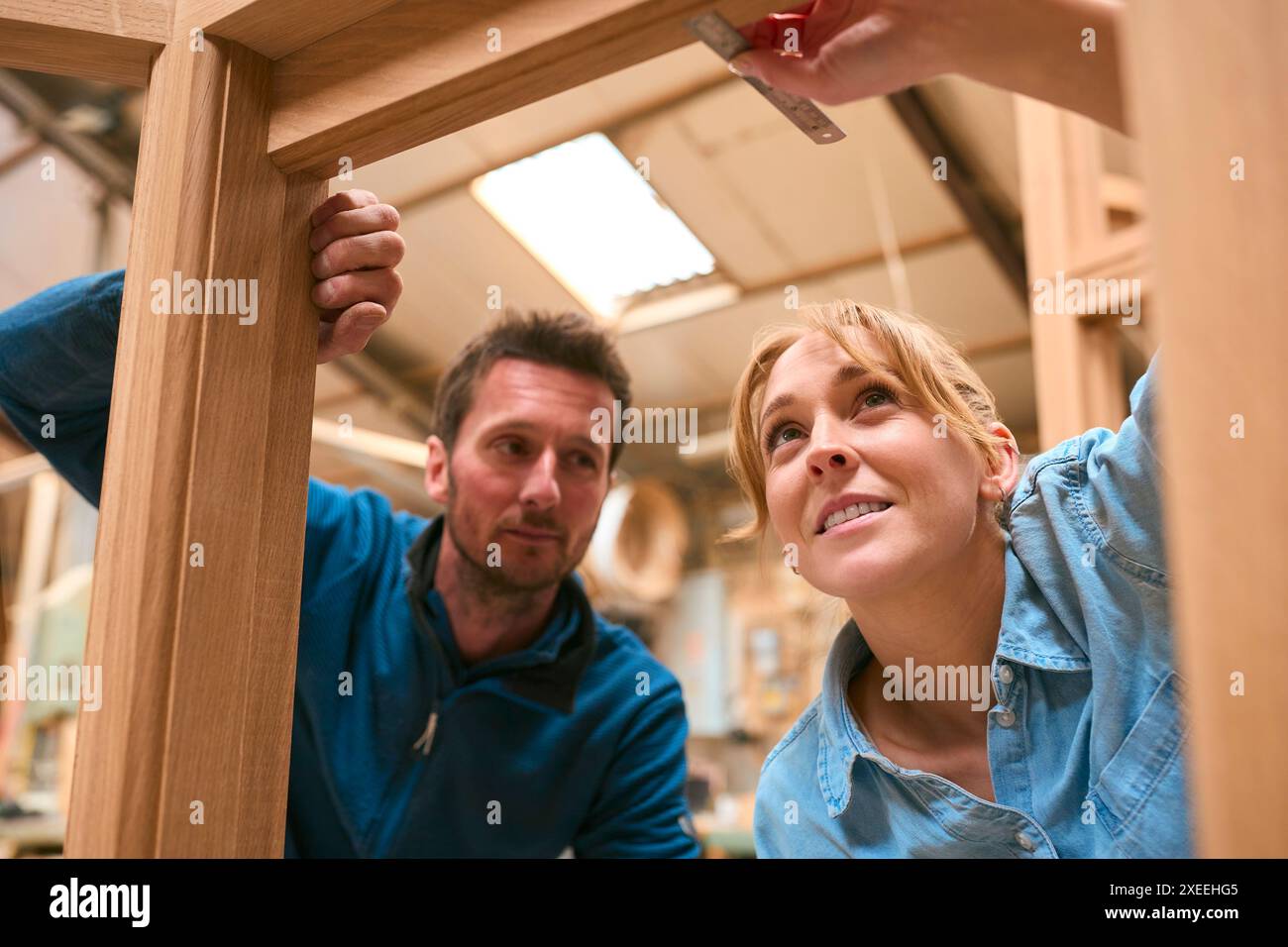 Carpenter With Female Apprentice In Workshop Using Ruler To Measure ...