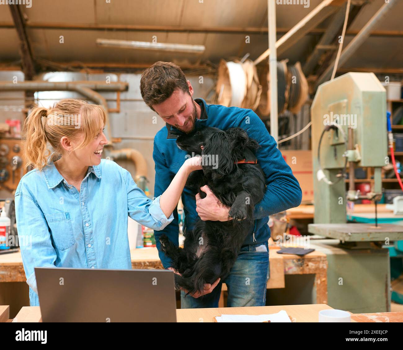 Male And Female Carpenters With Pet Spaniel Working In Woodwork ...