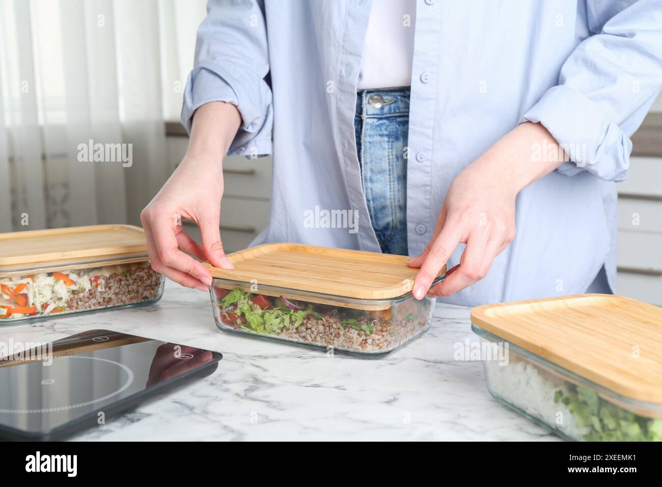 Healthy food. Woman closing glass container with meal at white marble ...
