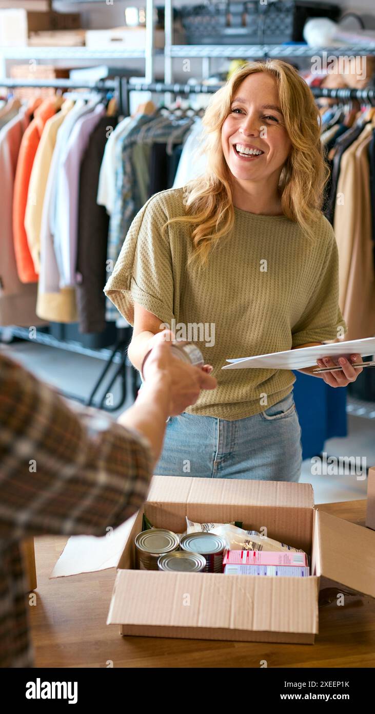 Female Charity Worker Receiving Food Donations From Member Of Public At ...