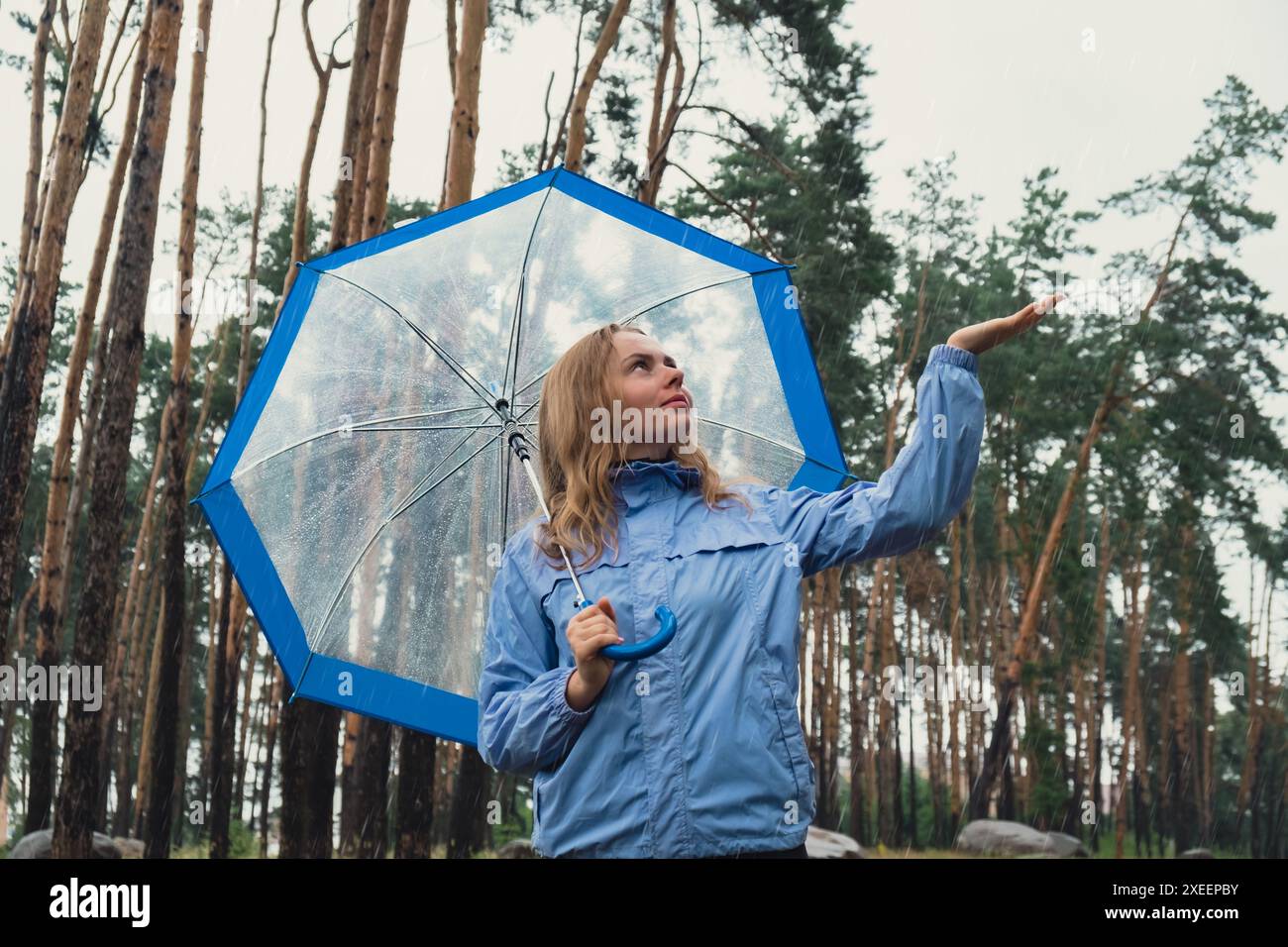Blonde girl checking the weather under transparent umbrella outside in ...