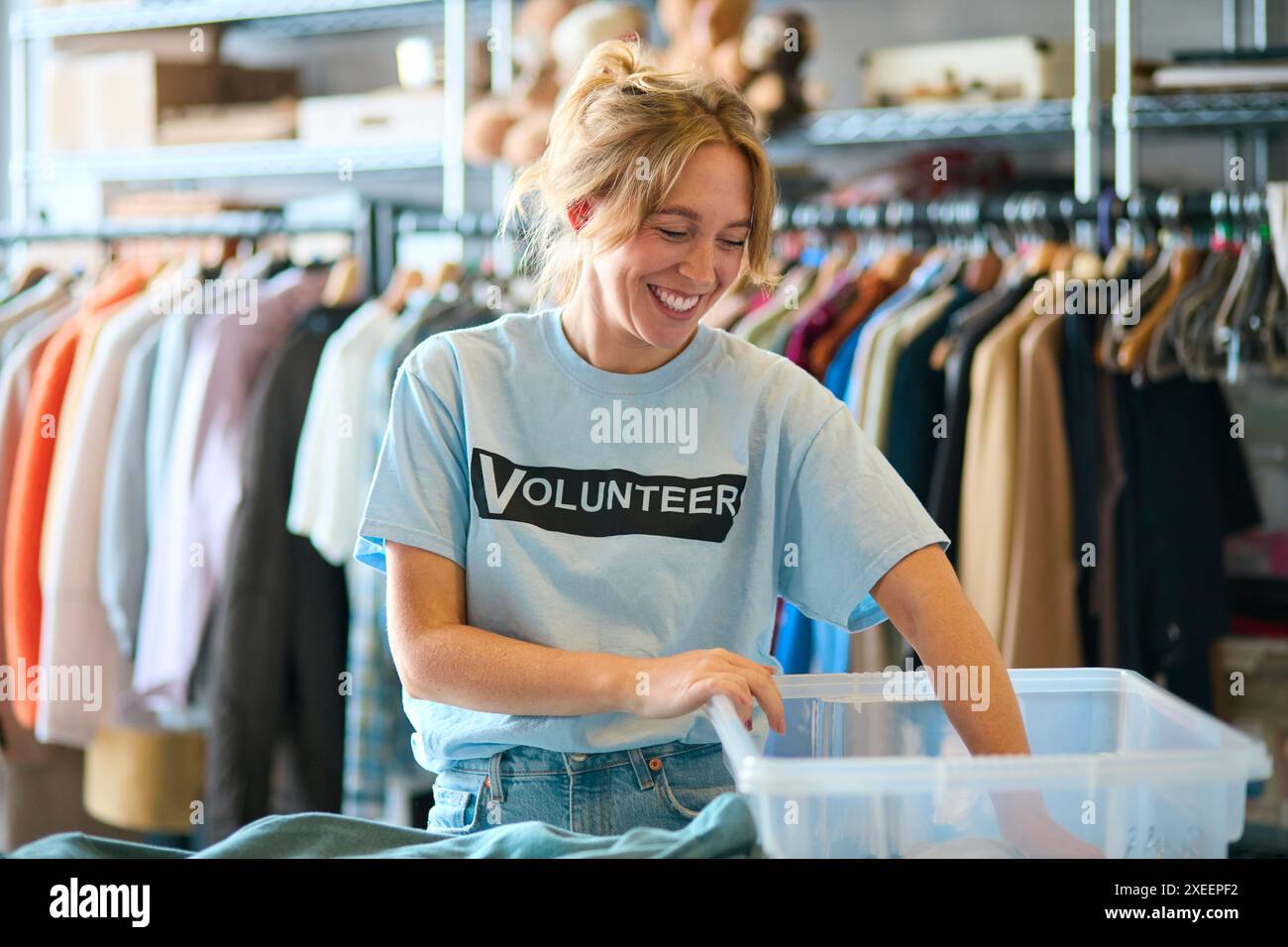Female Charity Worker Sorting Clothing Donations At Thrift Store Stock ...