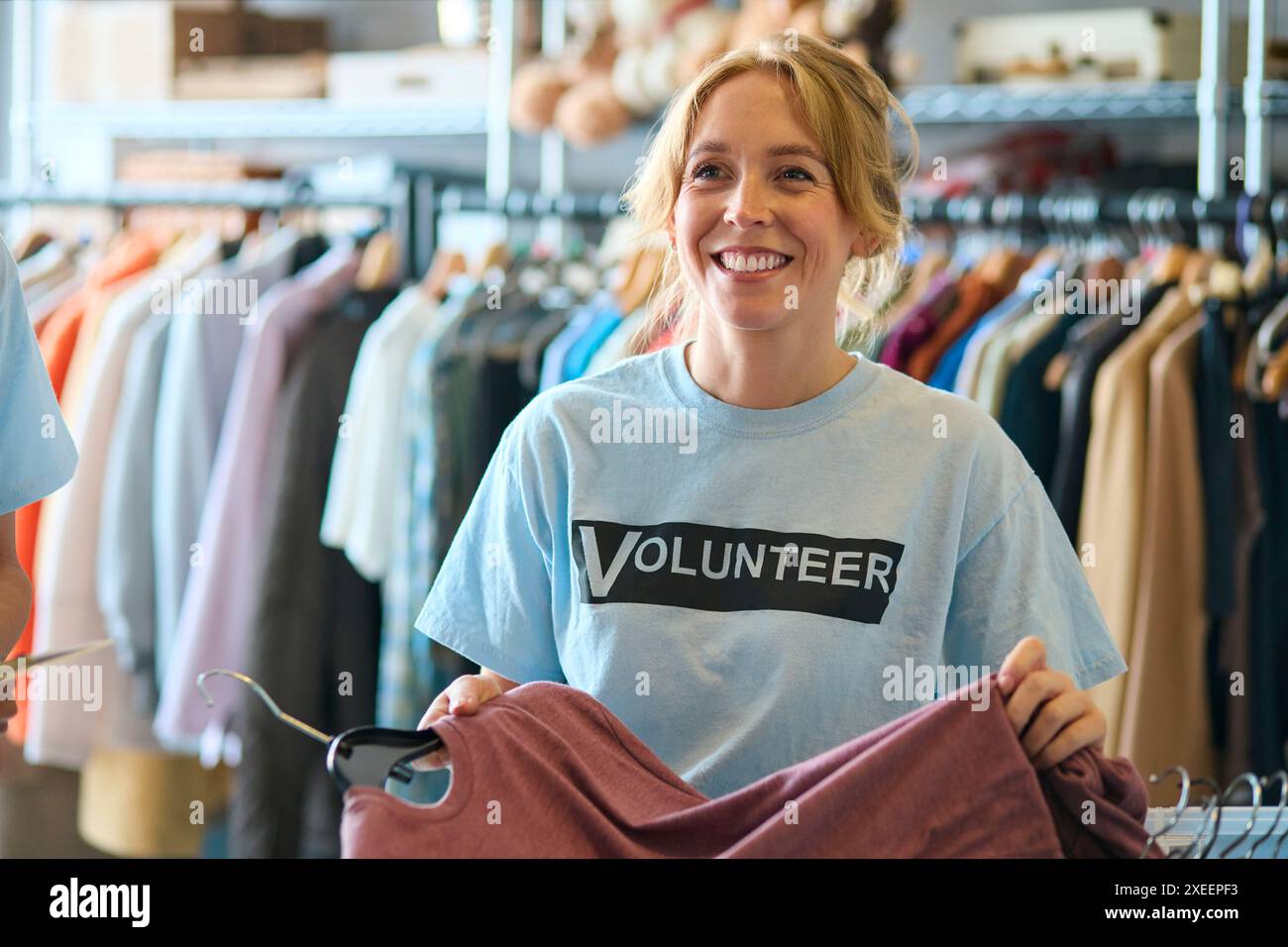 Female Charity Worker Checking Clothing Donations At Thrift Store Stock ...