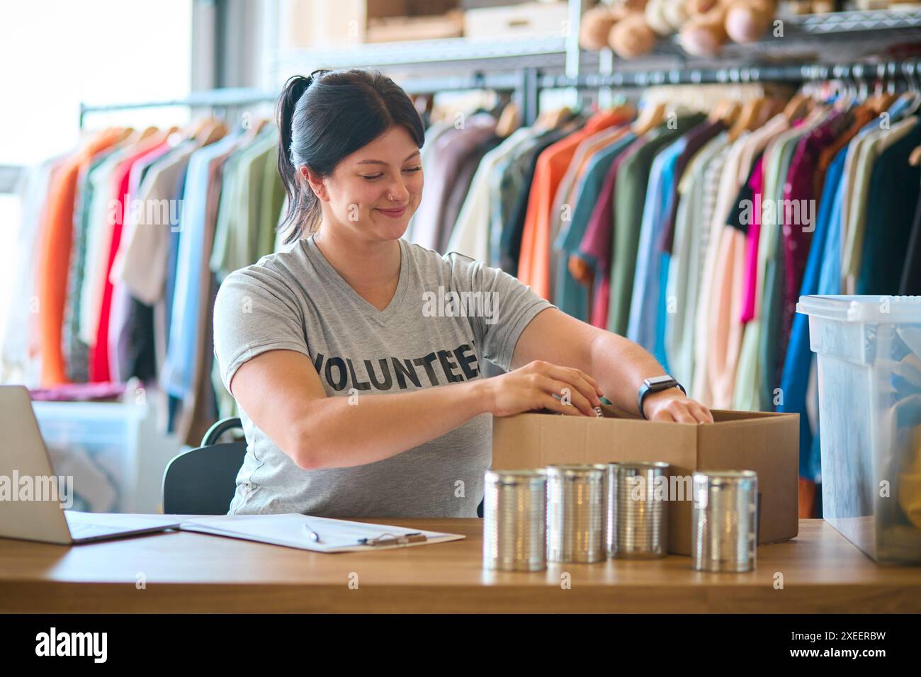 Female Charity Worker At Desk With Laptop Checking Food Donations At ...
