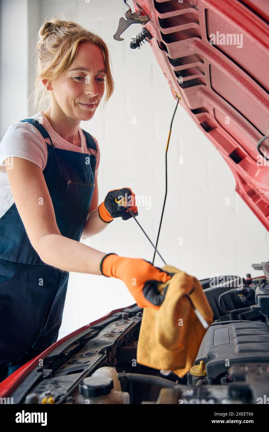 Female Car Auto Mechanic Looking Under Bonnet Of Car Checking Oil Level With Dipstick Stock ...