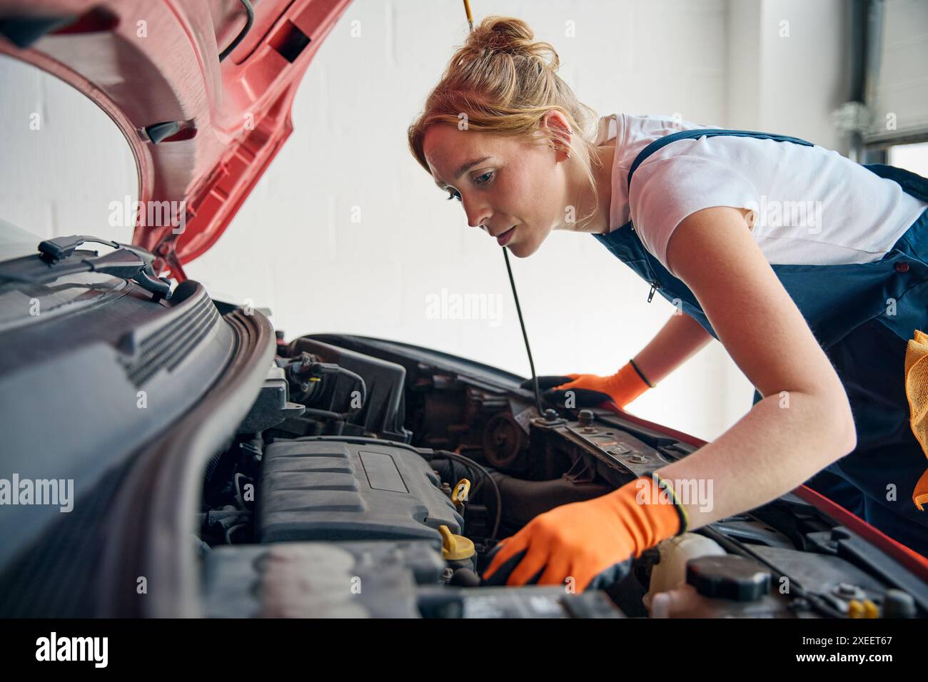 Female Car Auto Mechanic Looking At Engine Under Bonnet Of Car Being ...