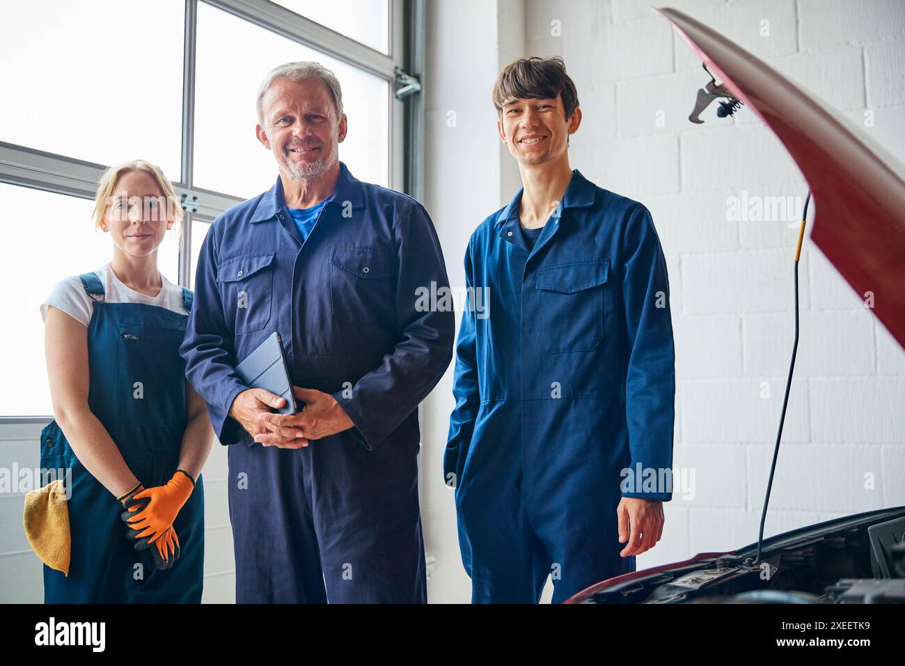 Portrait Of Team Of Car Auto Mechanics In Garage With Trainee Holding ...